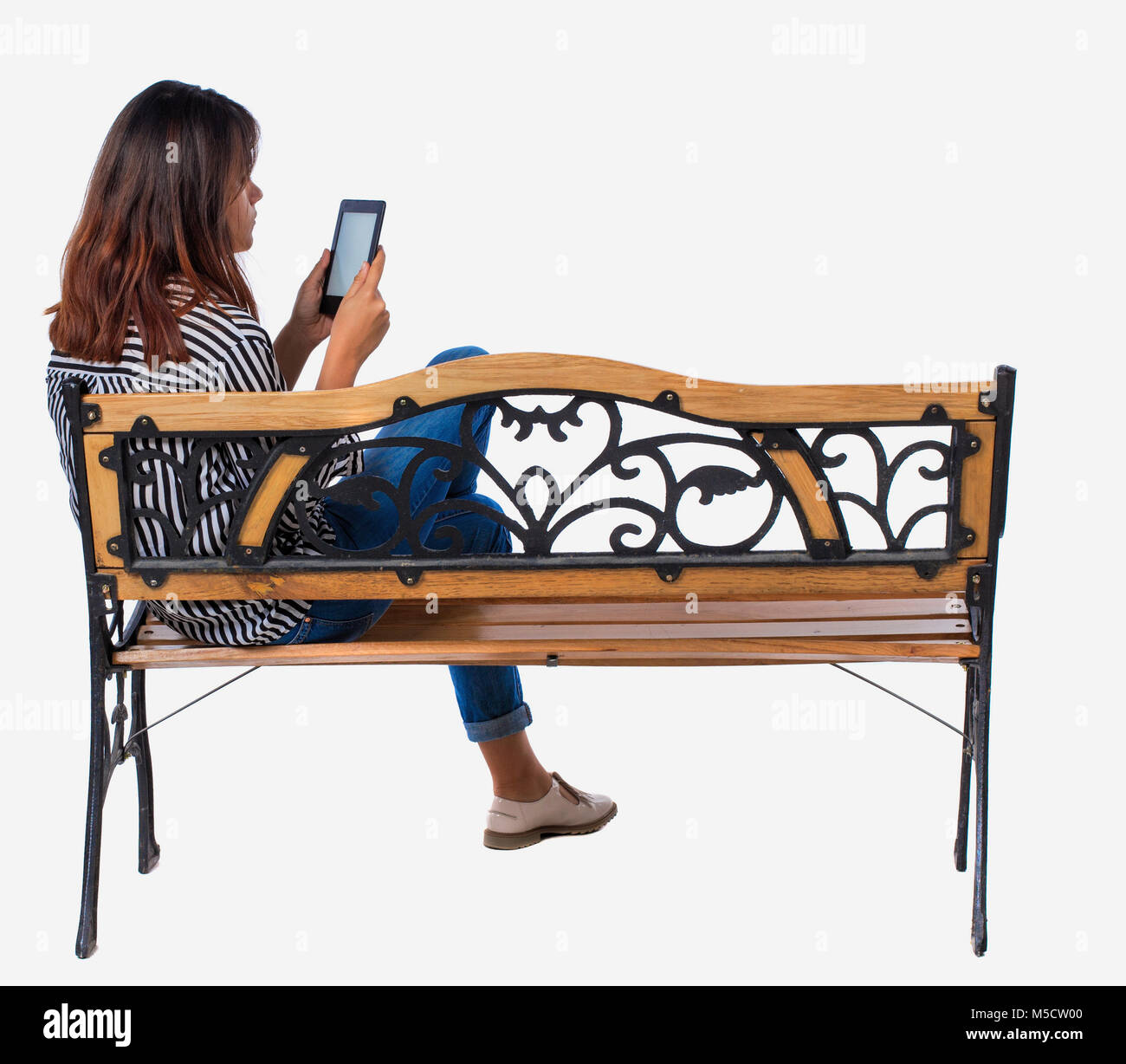 back view of woman sitting on bench and looks at the screen of the ...