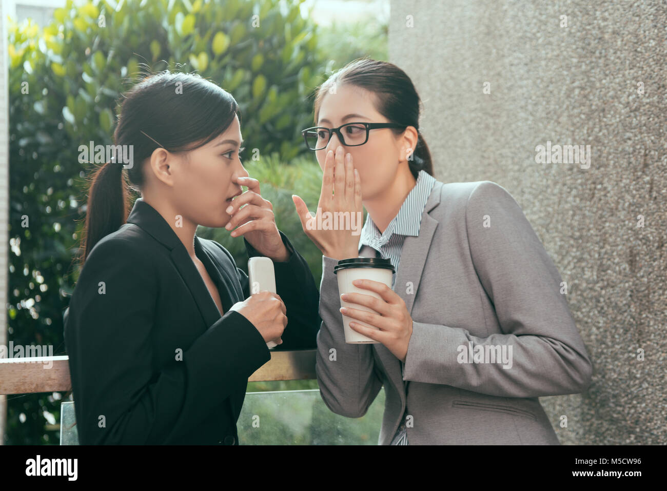 two beautiful Asian women talking about office gossip at break time ...
