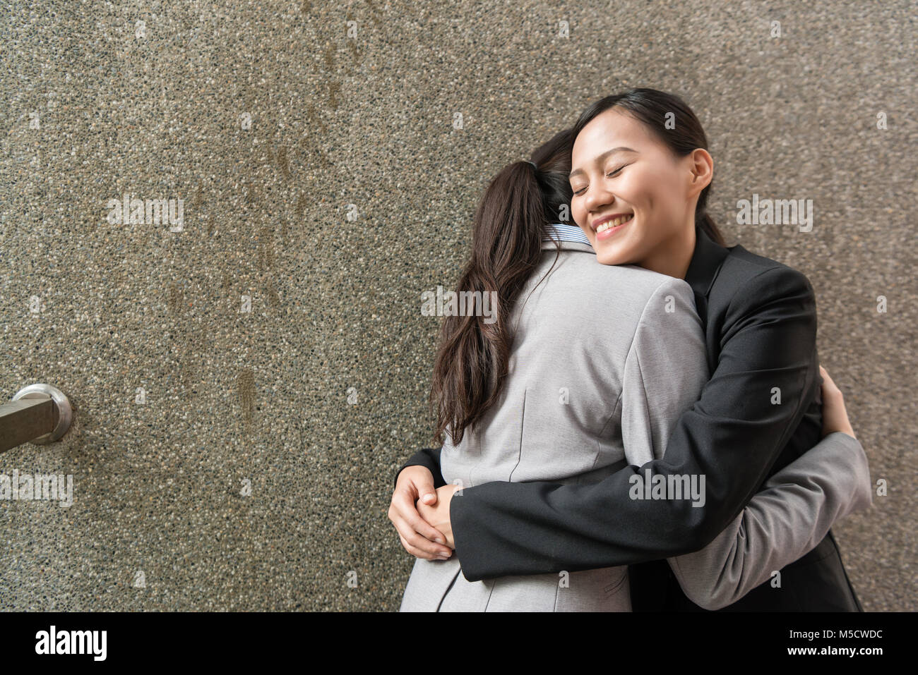 Asian woman manager try to comfort console her coworker by giving her a ...