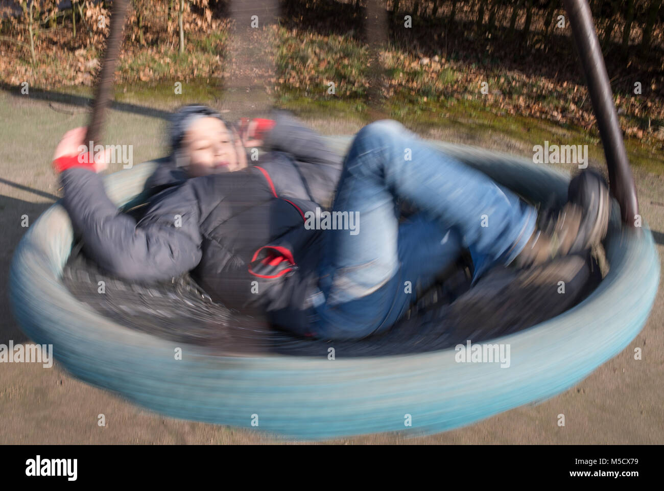 Boy swinging, whirling on a swing, playground. Blurred by motion and ...