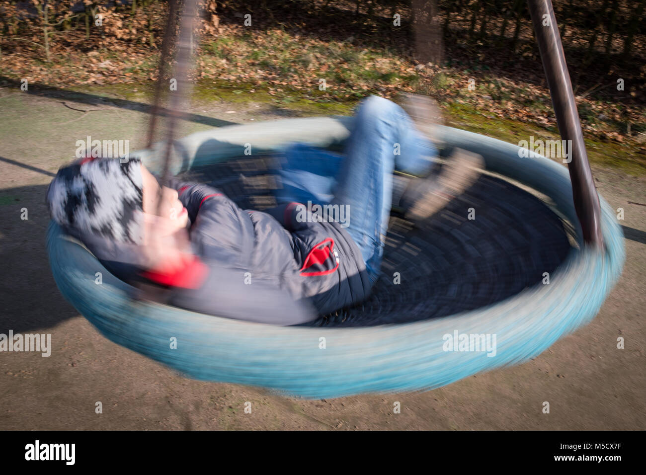 Boy swinging, whirling on a swing, playground. Blurred by motion and ...