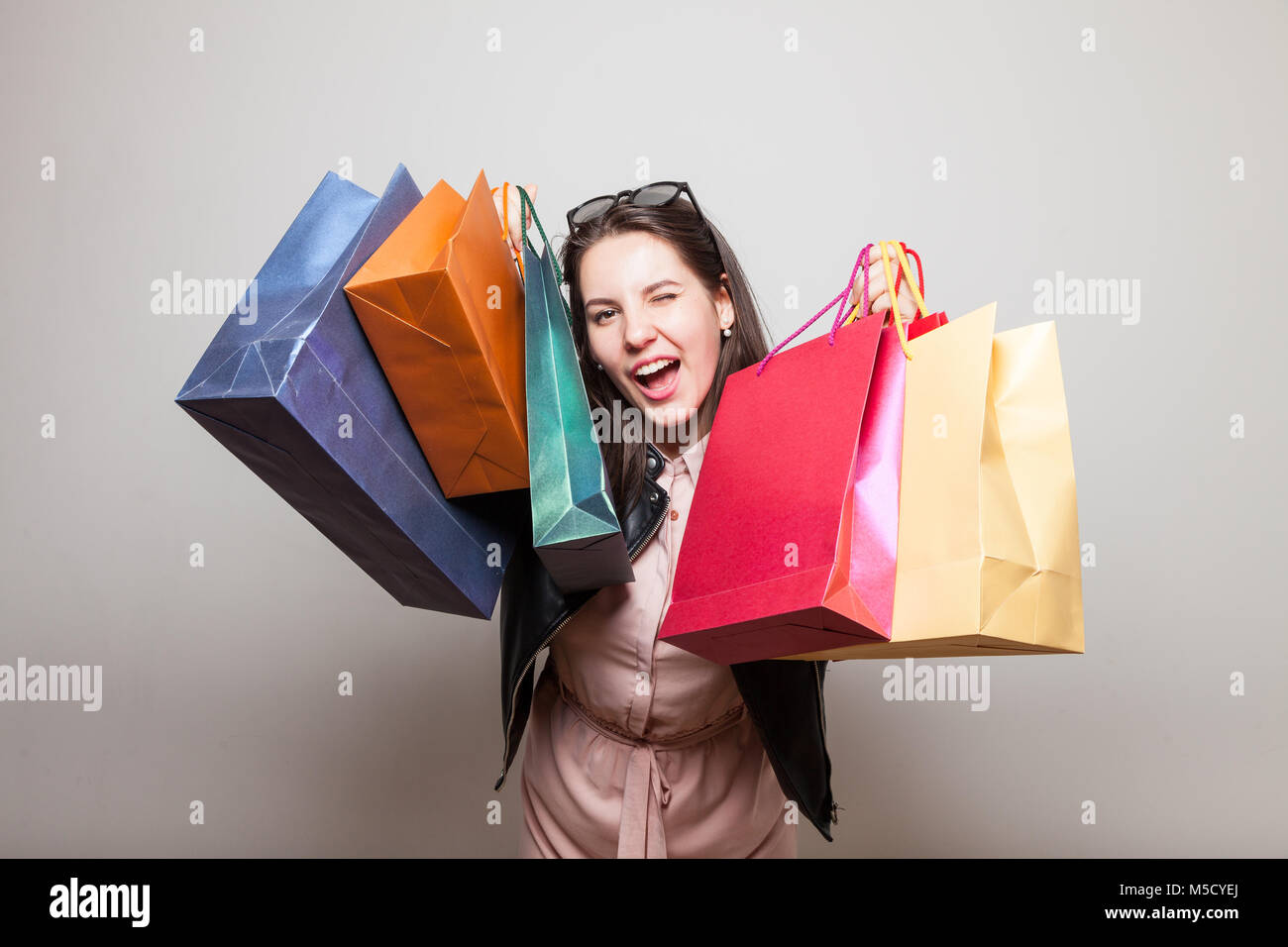 Cute girl winks with color bags Stock Photo - Alamy