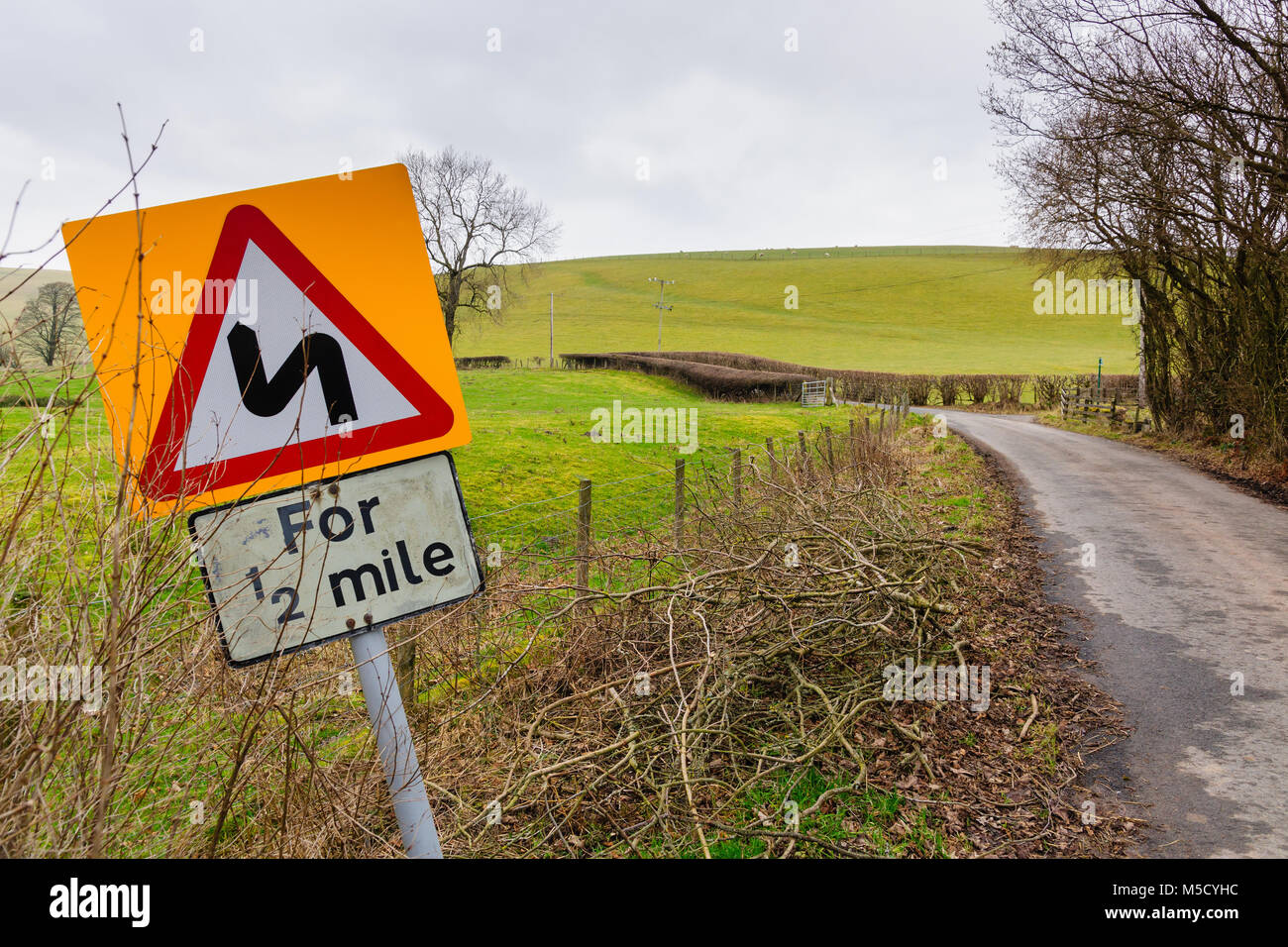 A narrow rural road in North Wales UK with a dilapidated warning sign ...