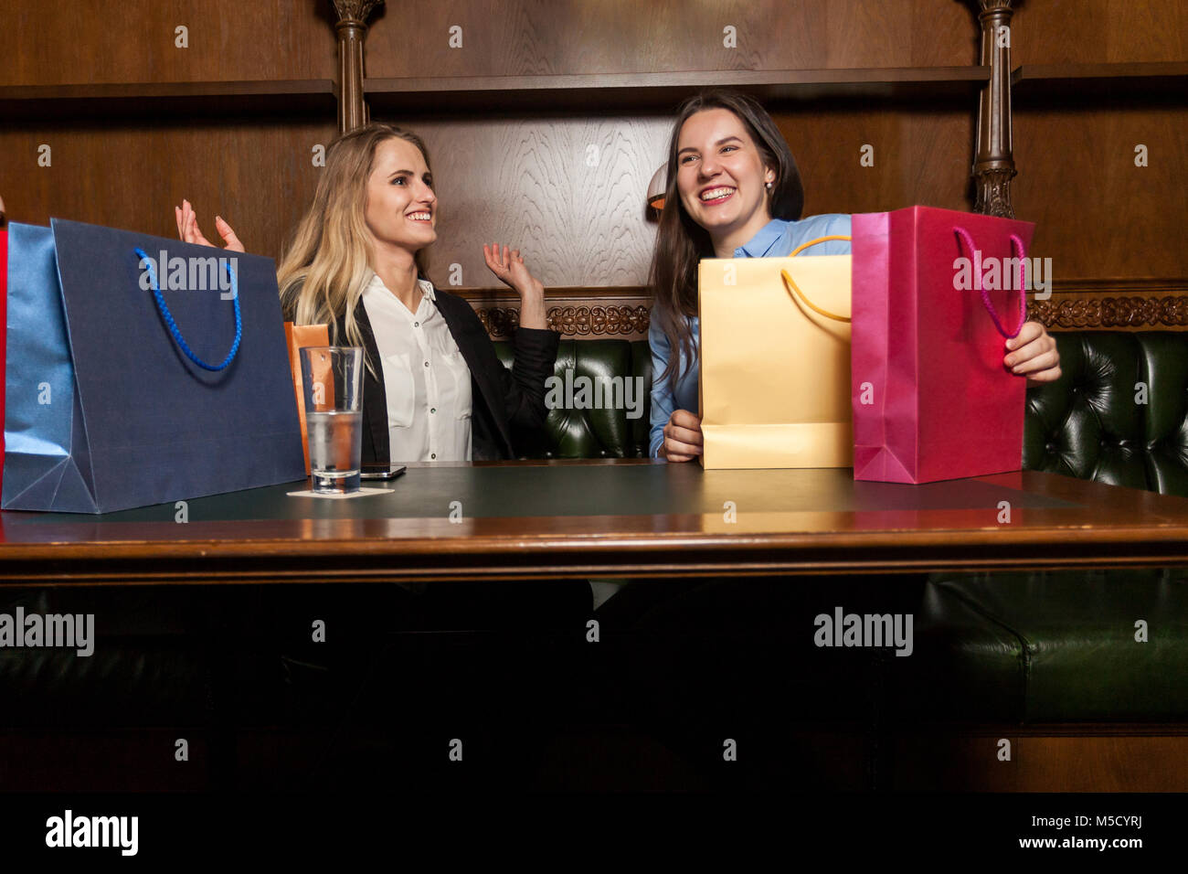 Laughing girls sitting in a cafe with presents Stock Photo - Alamy