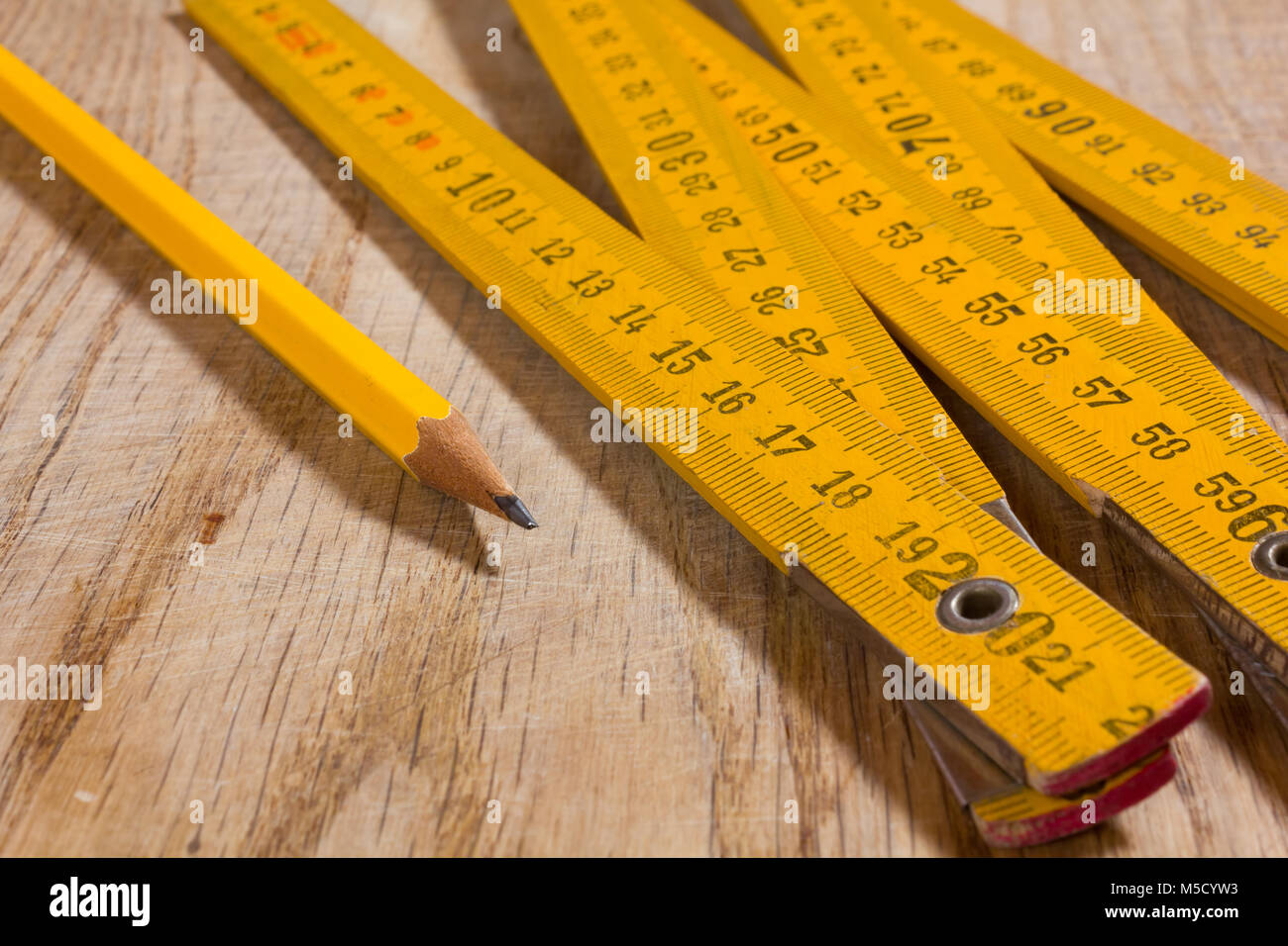 A yellow measuring stick and a pencil on an old wooden table Stock ...