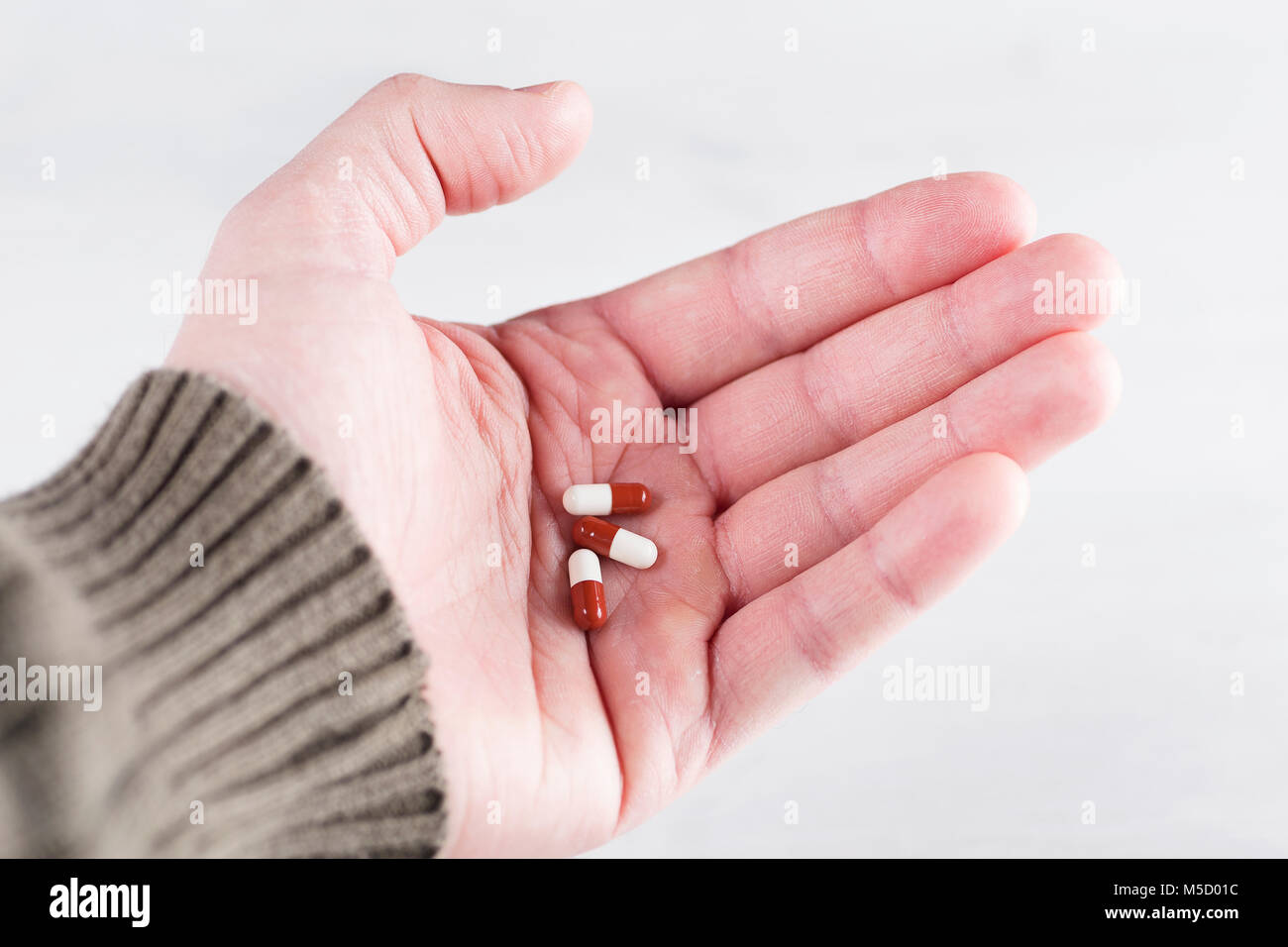 A hand holding three pills on a white background Stock Photo - Alamy