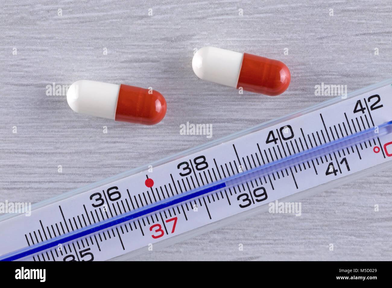 Pills and a detail of a medical thermometer showing a high temperature ...