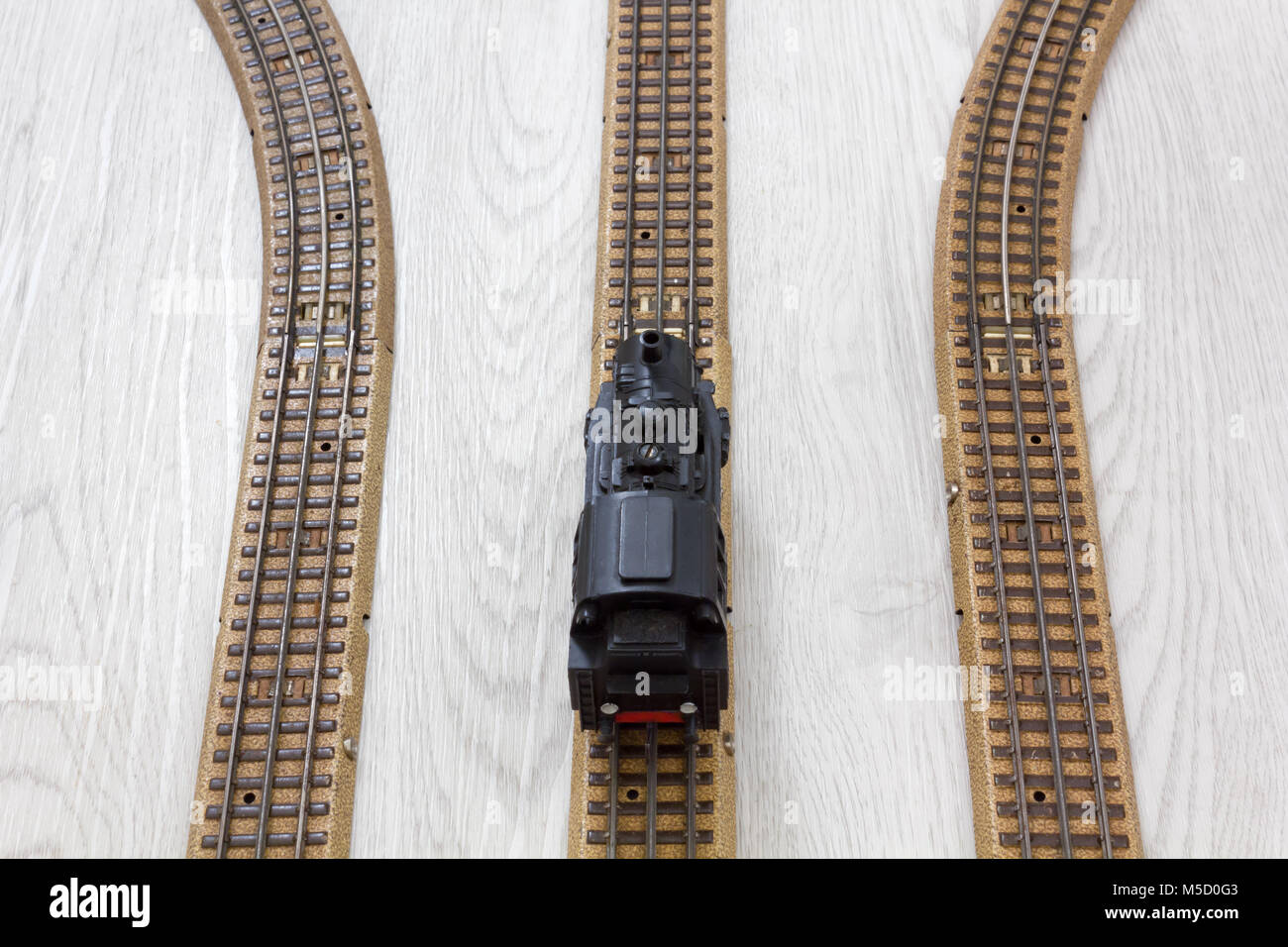 1950s vintage model steam locomotive on the rails over a wooden texture ...