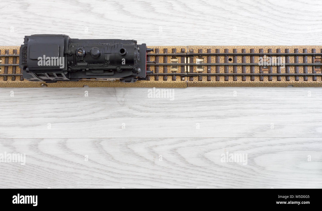 1950s vintage model steam locomotive on the rails over a wooden texture ...