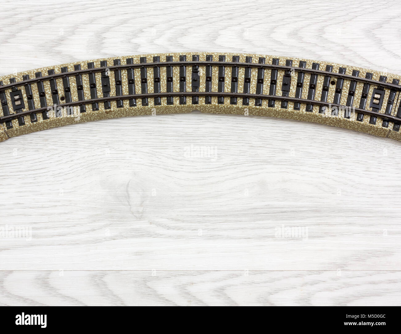 Miniature rails for electric model train over a wooden texture floor ...