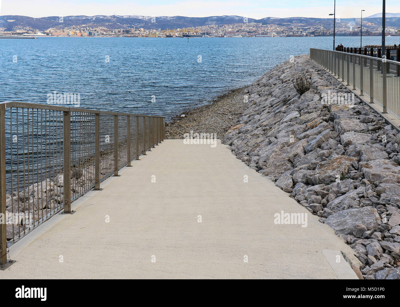 Coastline with rocky beach and path with metal fence Stock Photo - Alamy