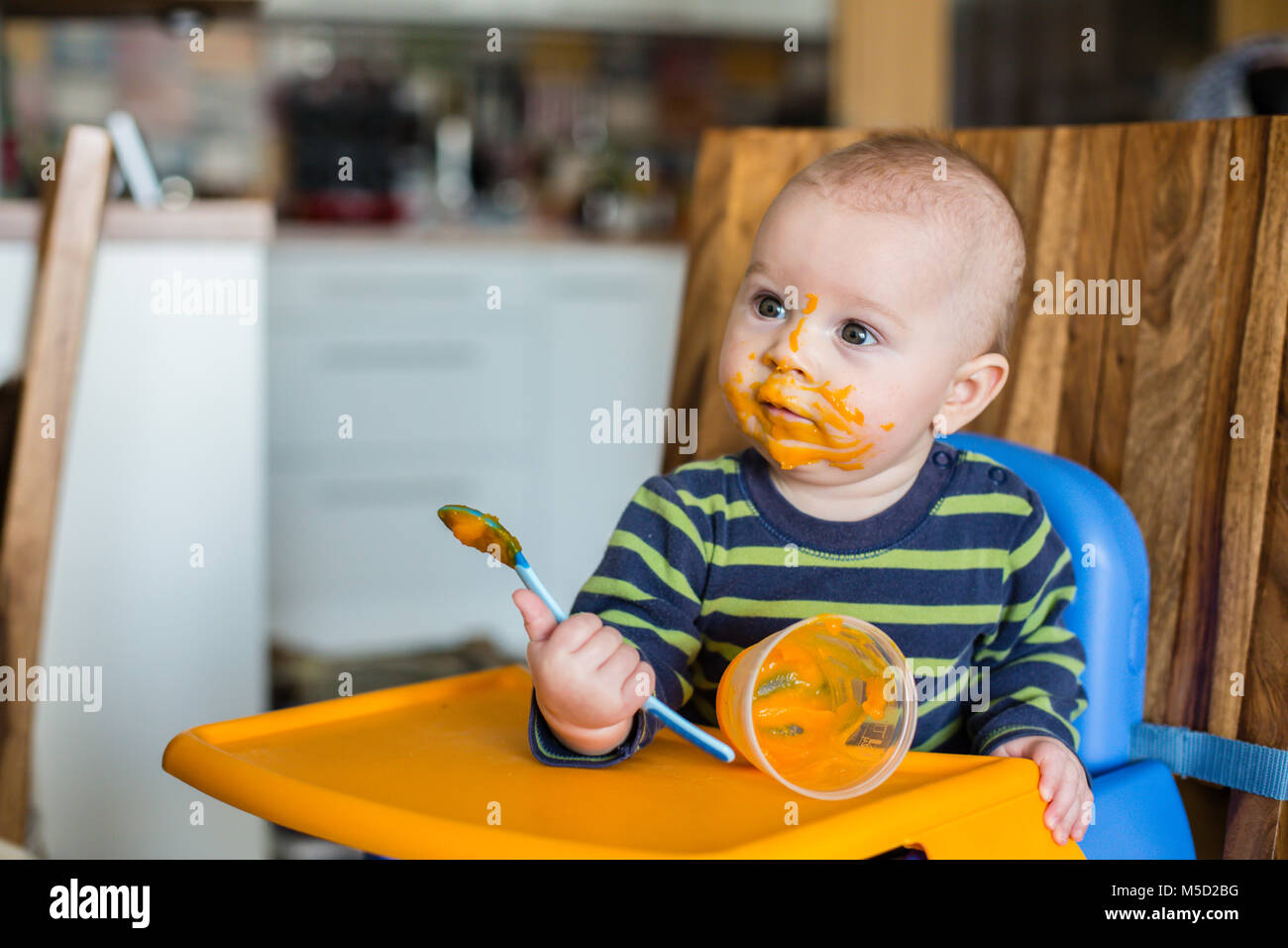 Little baby boy, eating mashed food for the first time in his life ...