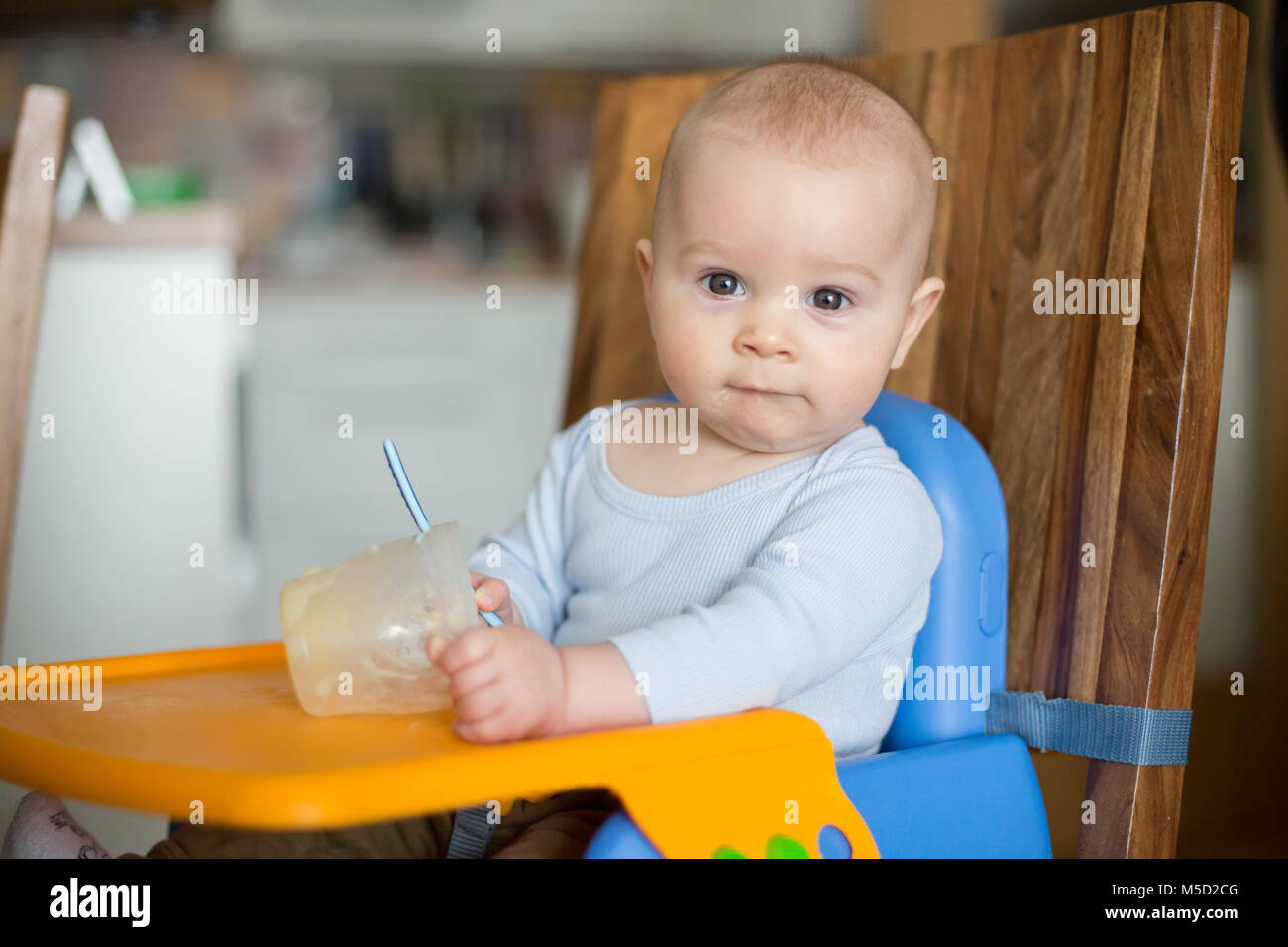 Little baby boy, eating mashed food for the first time in his life ...