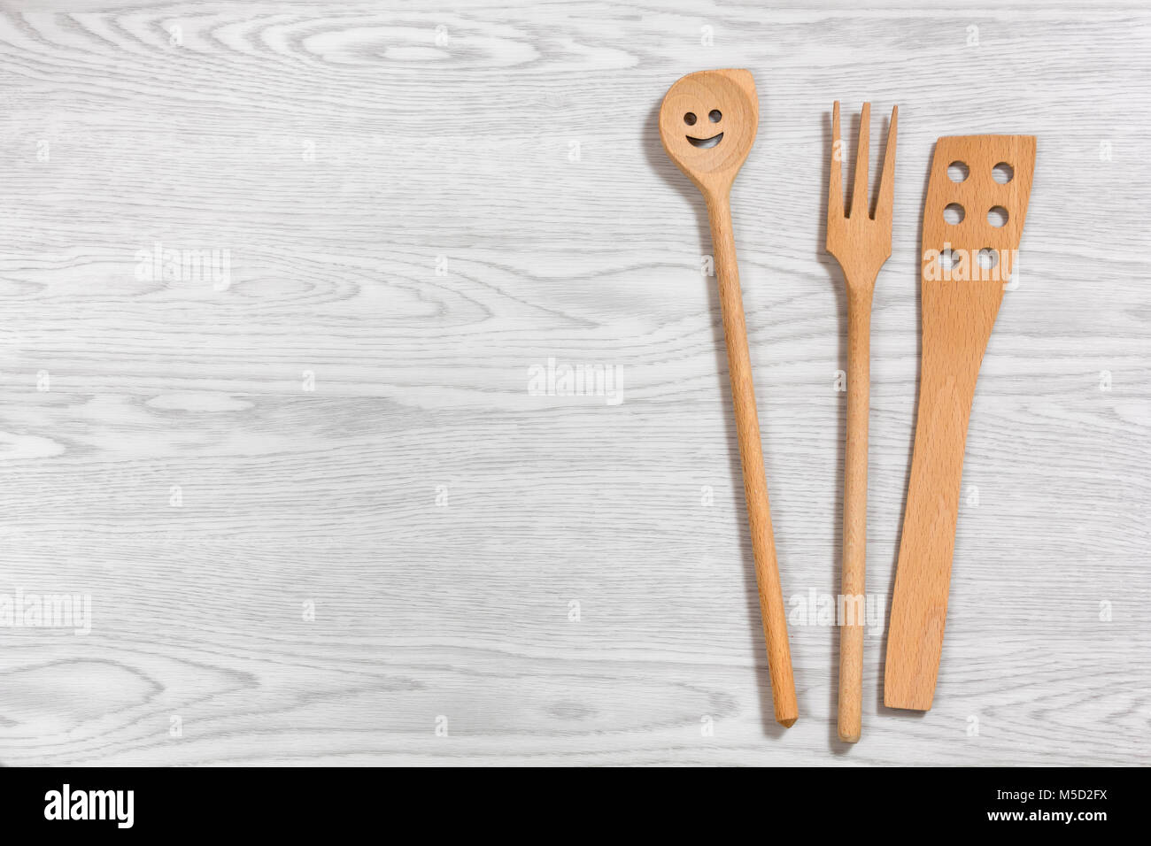 Wooden Spoon with a smiling face and two other kitchen utensils on a ...