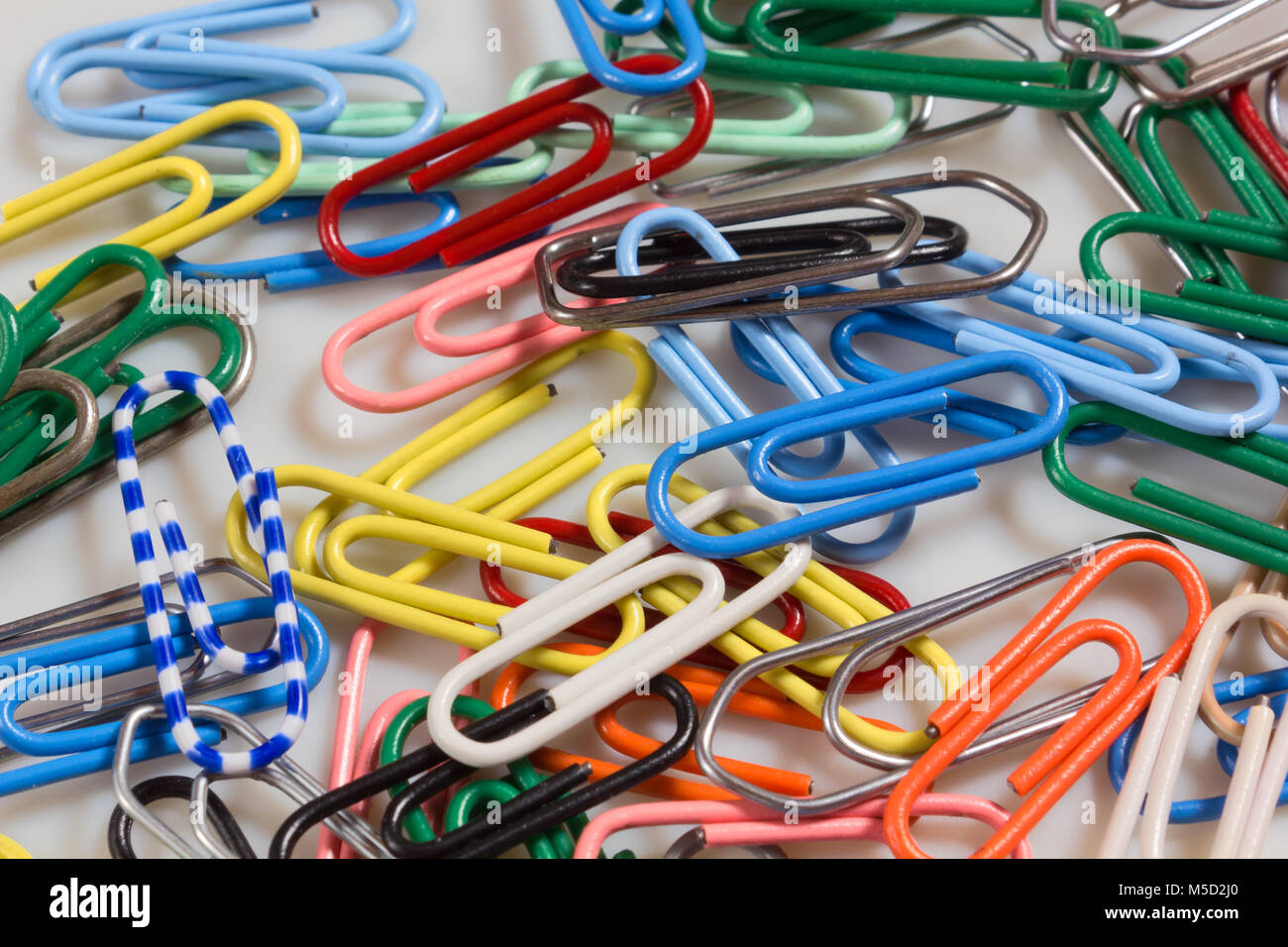 Colored paperclips scattered across a white background Stock Photo - Alamy