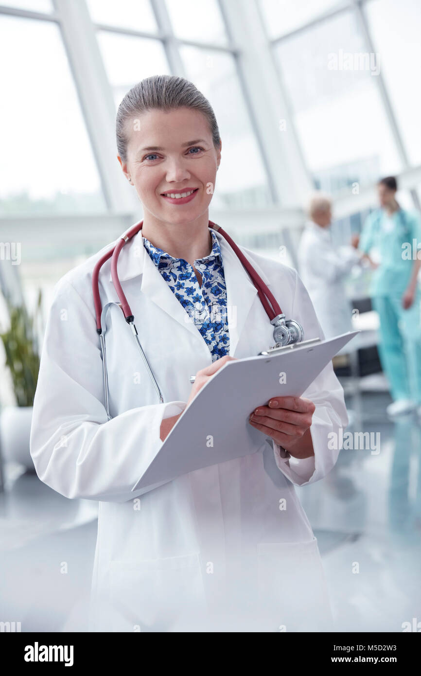 Portrait smiling, confident female doctor with clipboard in hospital ...