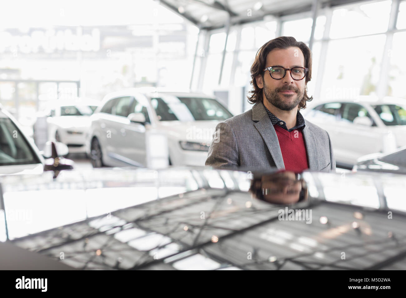 Portrait smiling, confident car salesman in car dealership showroom ...