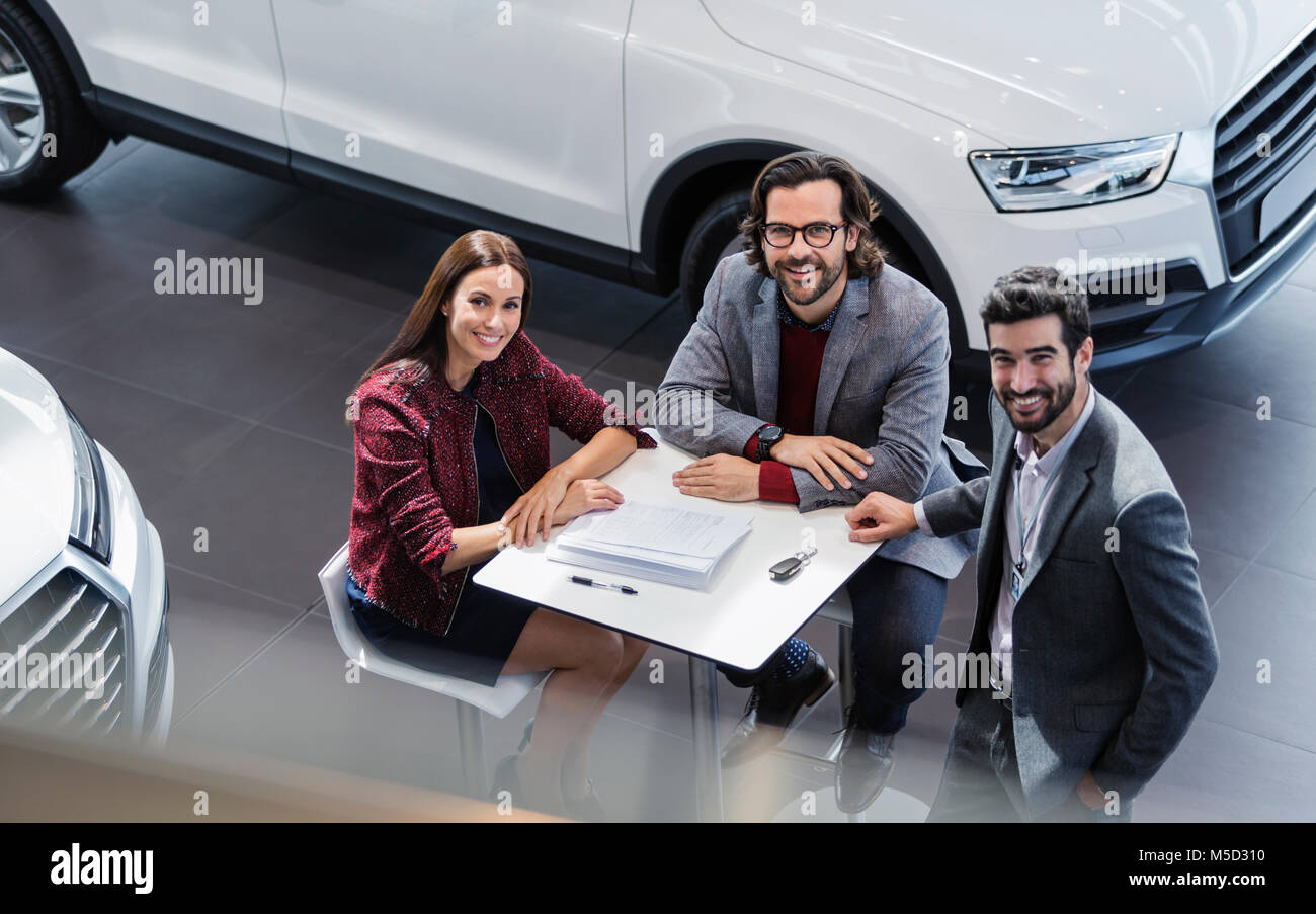 Portrait smiling car sales people meeting in car dealership showroom ...