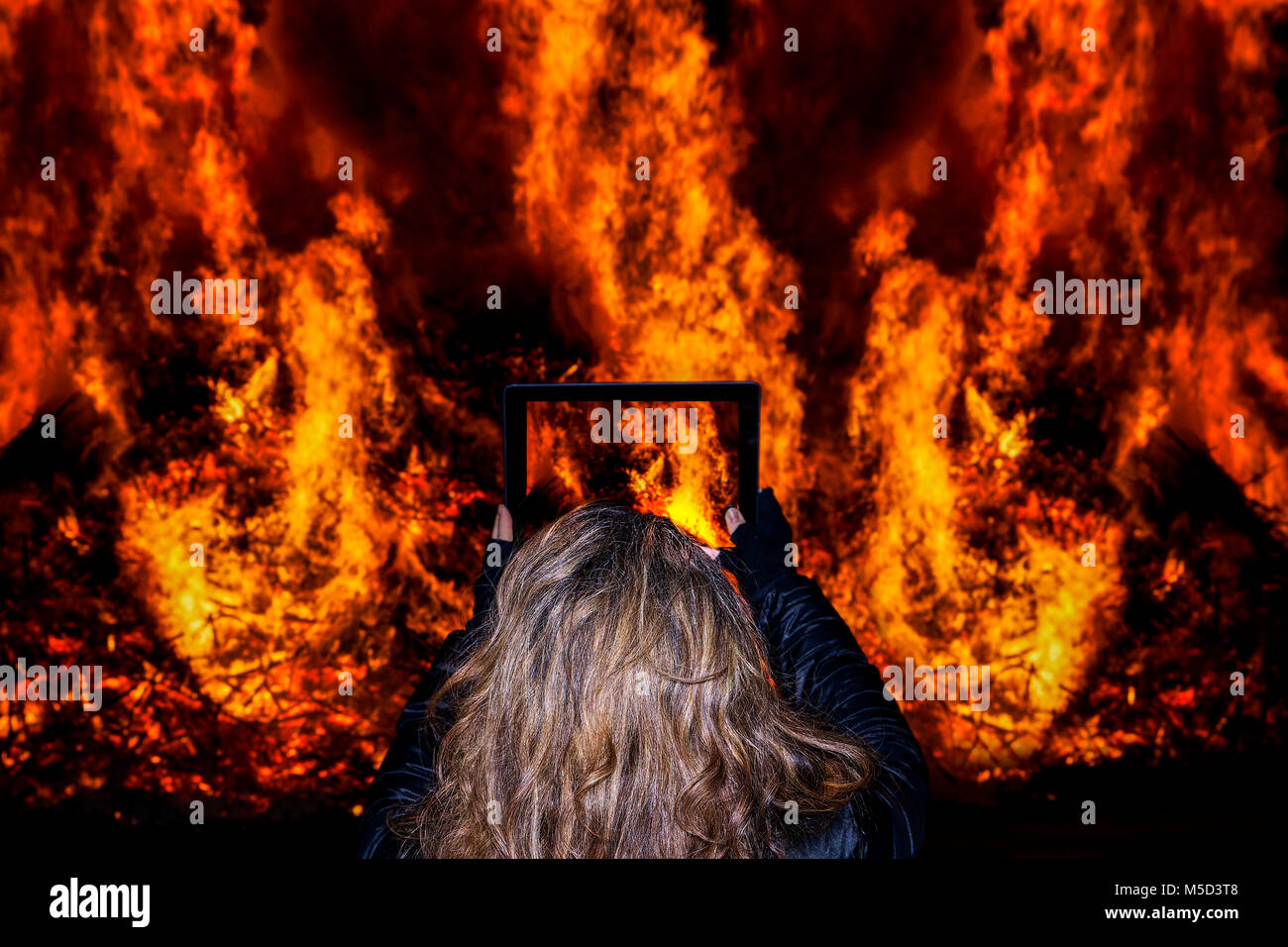 Attractive woman takes a selfie in front of a big fire during a ...