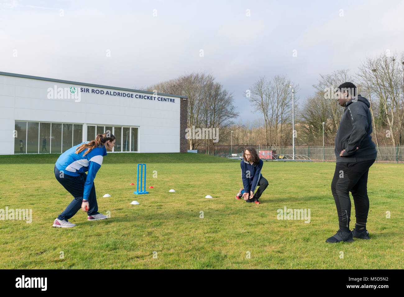 students practice playing cricket on a school playing field as part of ...