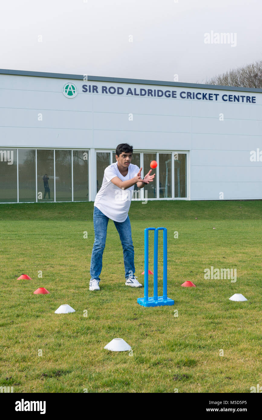 students practice playing cricket on a school playing field as part of ...