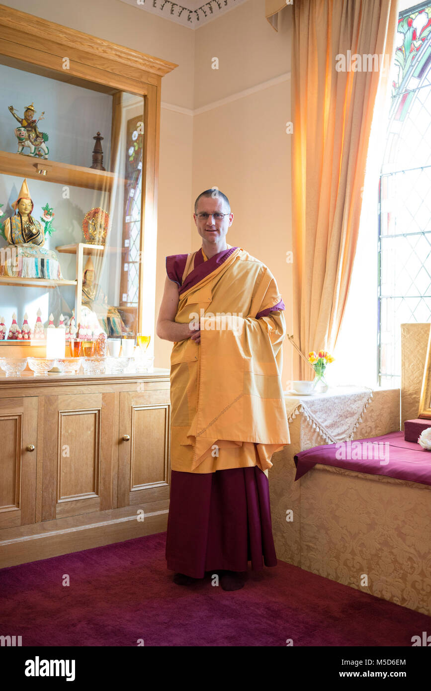 a buddist monk and teacher stands in his classroom in traditional robes ...