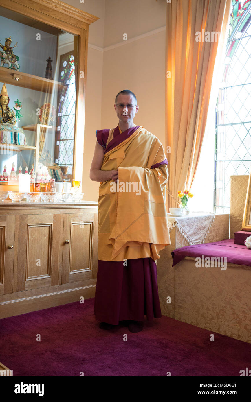 a buddist monk and teacher stands in his classroom in traditional robes ...
