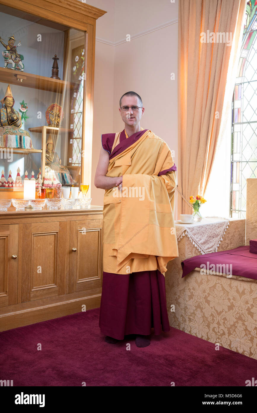 a buddist monk and teacher stands in his classroom in traditional robes ...
