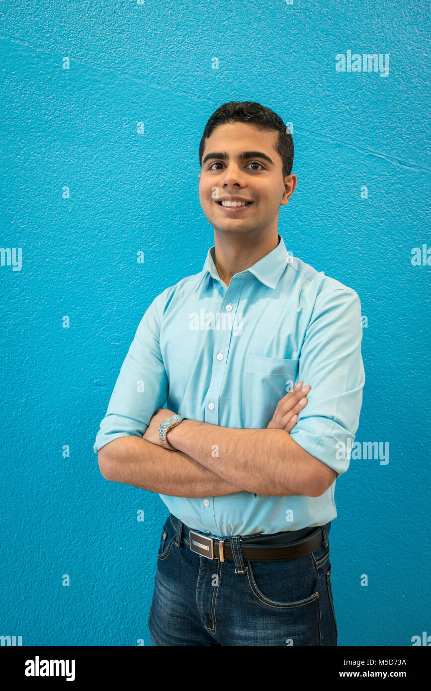 a short haired young confident, student stands with his arms folded in ...