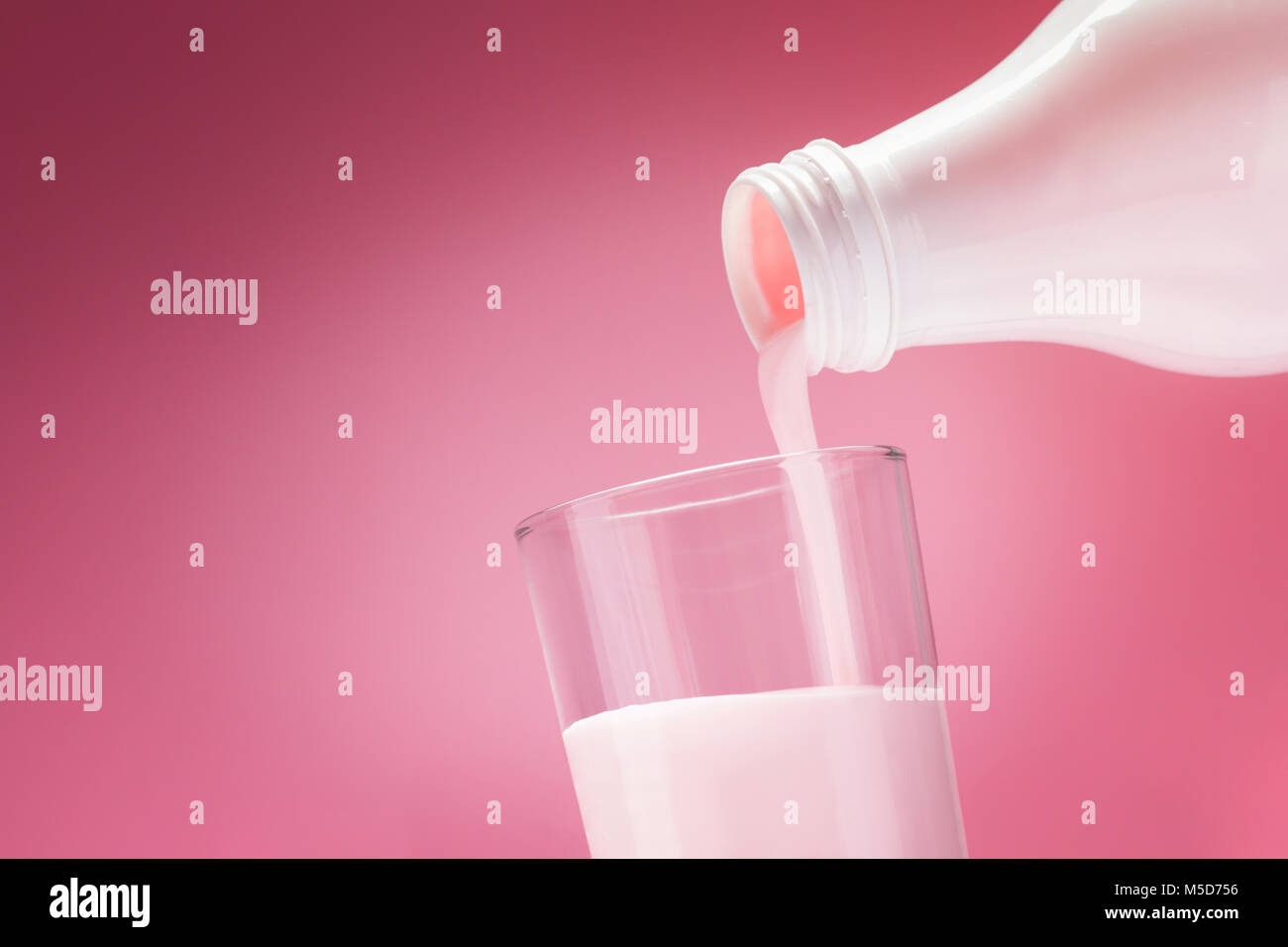 Pouring Yogurt From A White Bottle Into A Glass On A Pink Background ...