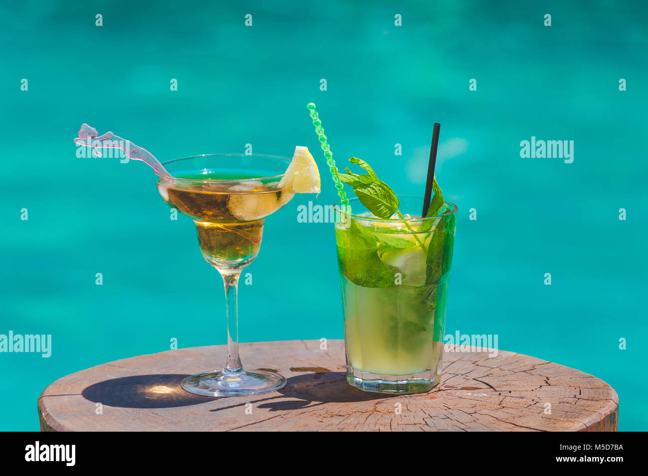Two cocktails on wooden table next to swimming pool Stock Photo - Alamy