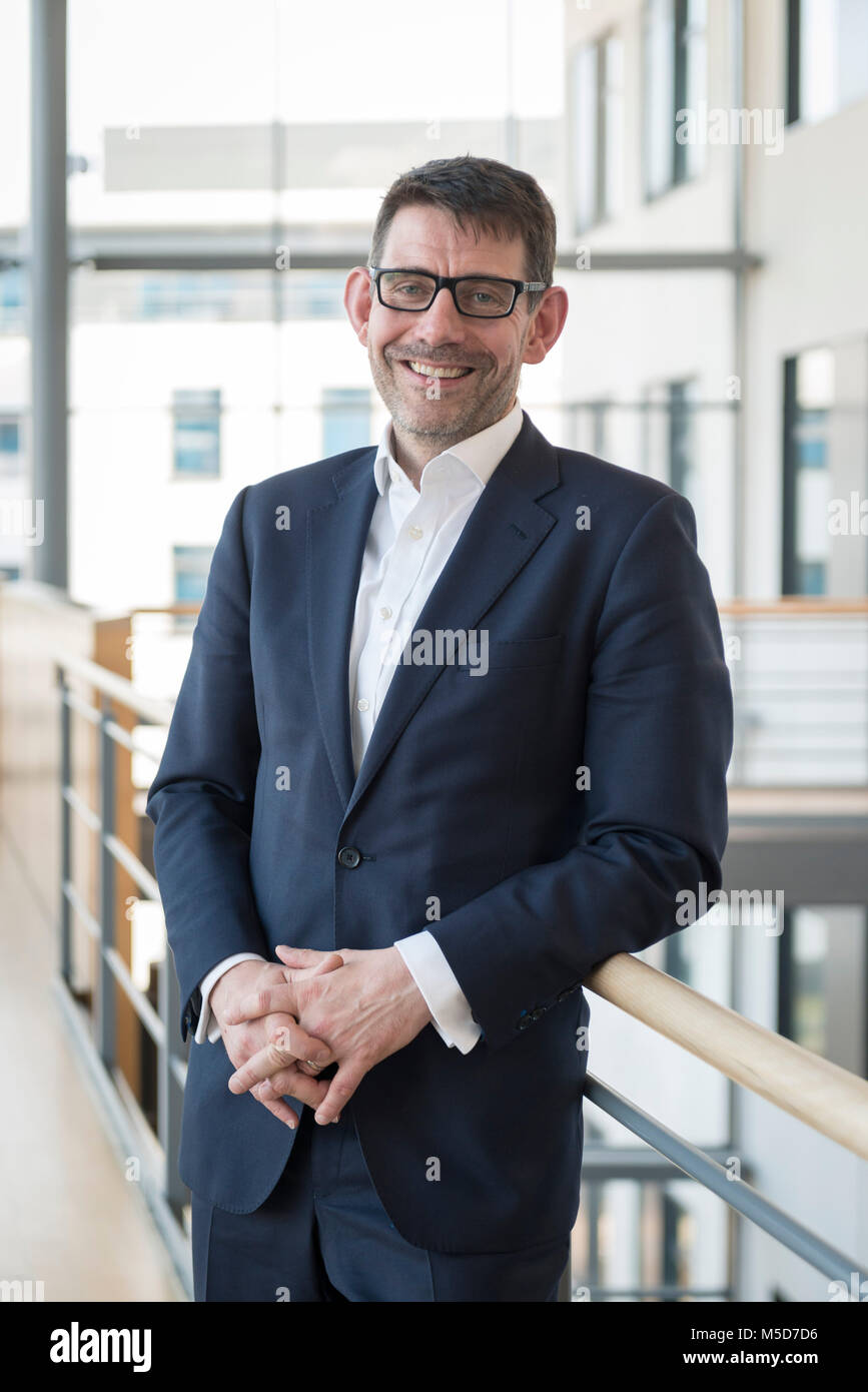 a relaxed office worker, support staff stands in a bright office ...