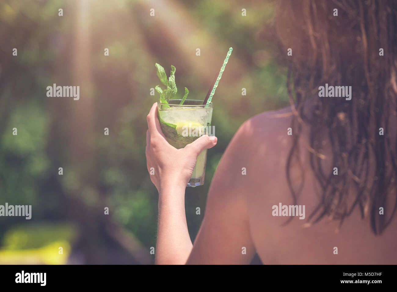 Rear view of female holding mojito cocktail. Summer vacation concept ...