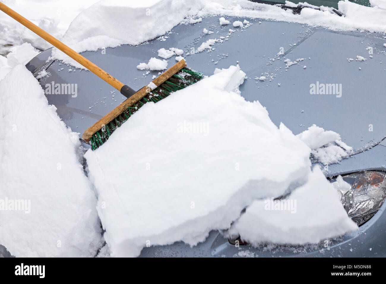Sweeping snowed car with a broom Stock Photo - Alamy