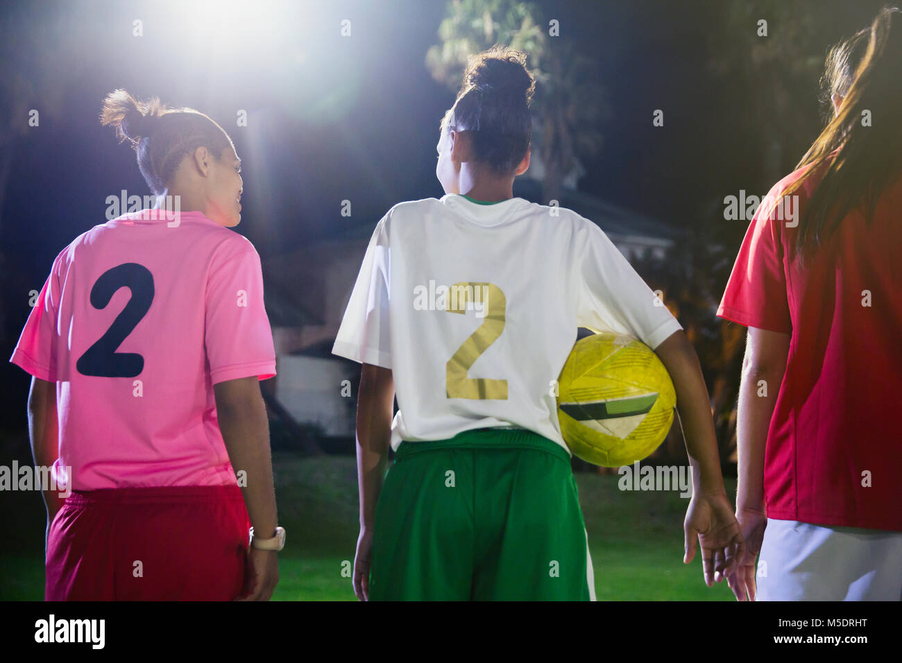 Young female soccer players with ball talking on field at night Stock ...