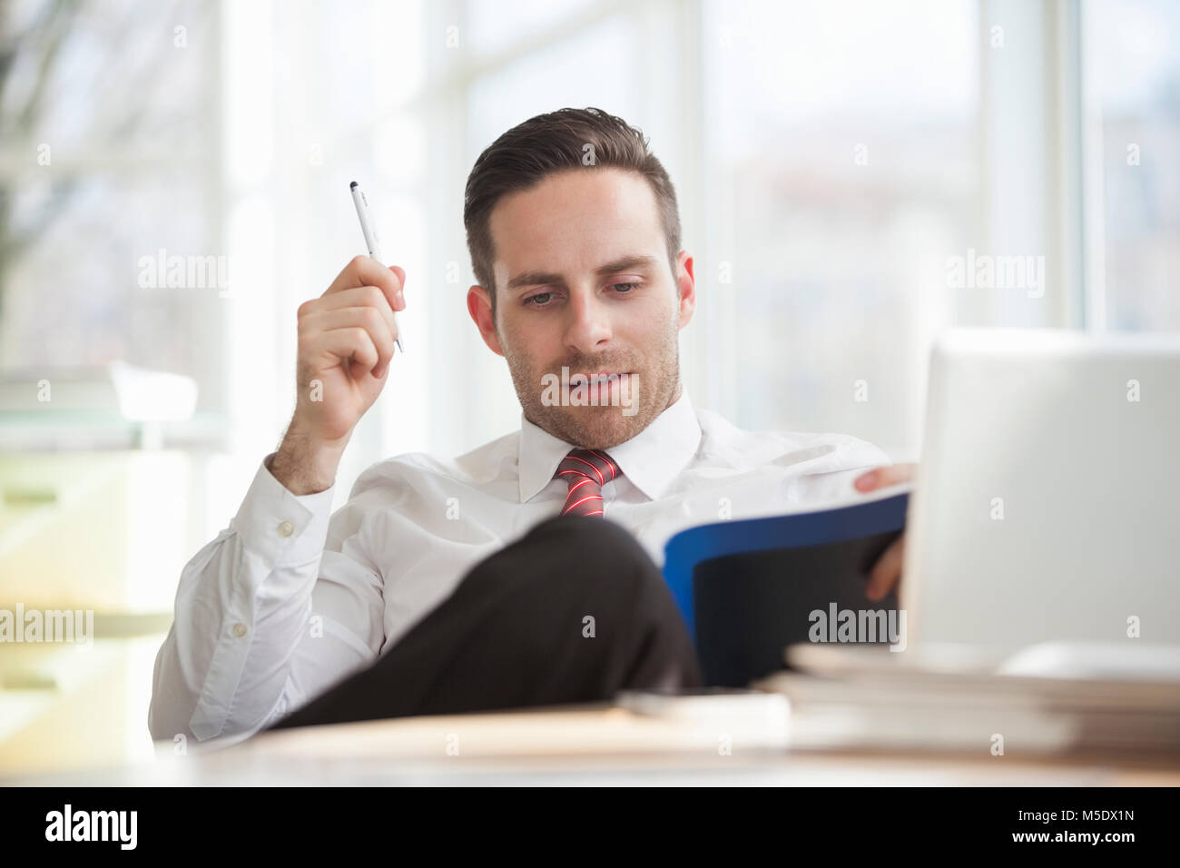 Young businessman reading book in office Stock Photo - Alamy