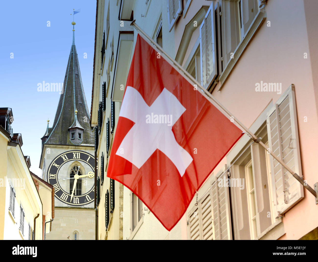 Clock tower of the St. Peter Church and Swiss Flag on the facade ...