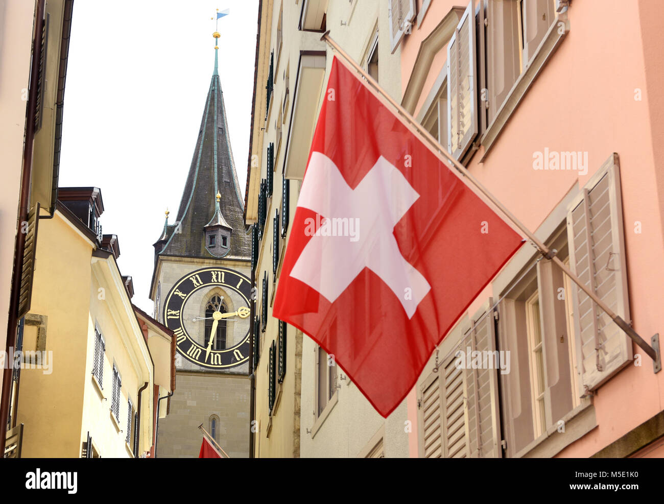 Clock tower of the St. Peter Church and Swiss Flag on the facade ...
