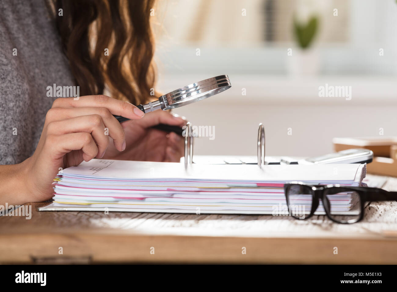 Close-up Of A Auditor Looking Invoice Through Magnifying Glass On Desk ...