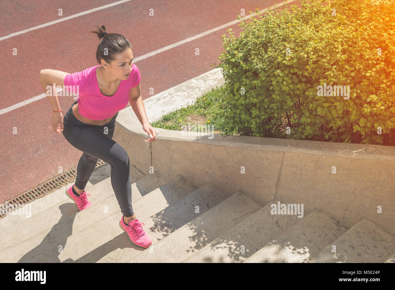 Muscular sportswoman running up on stairs. Morning workout. Urban scene ...