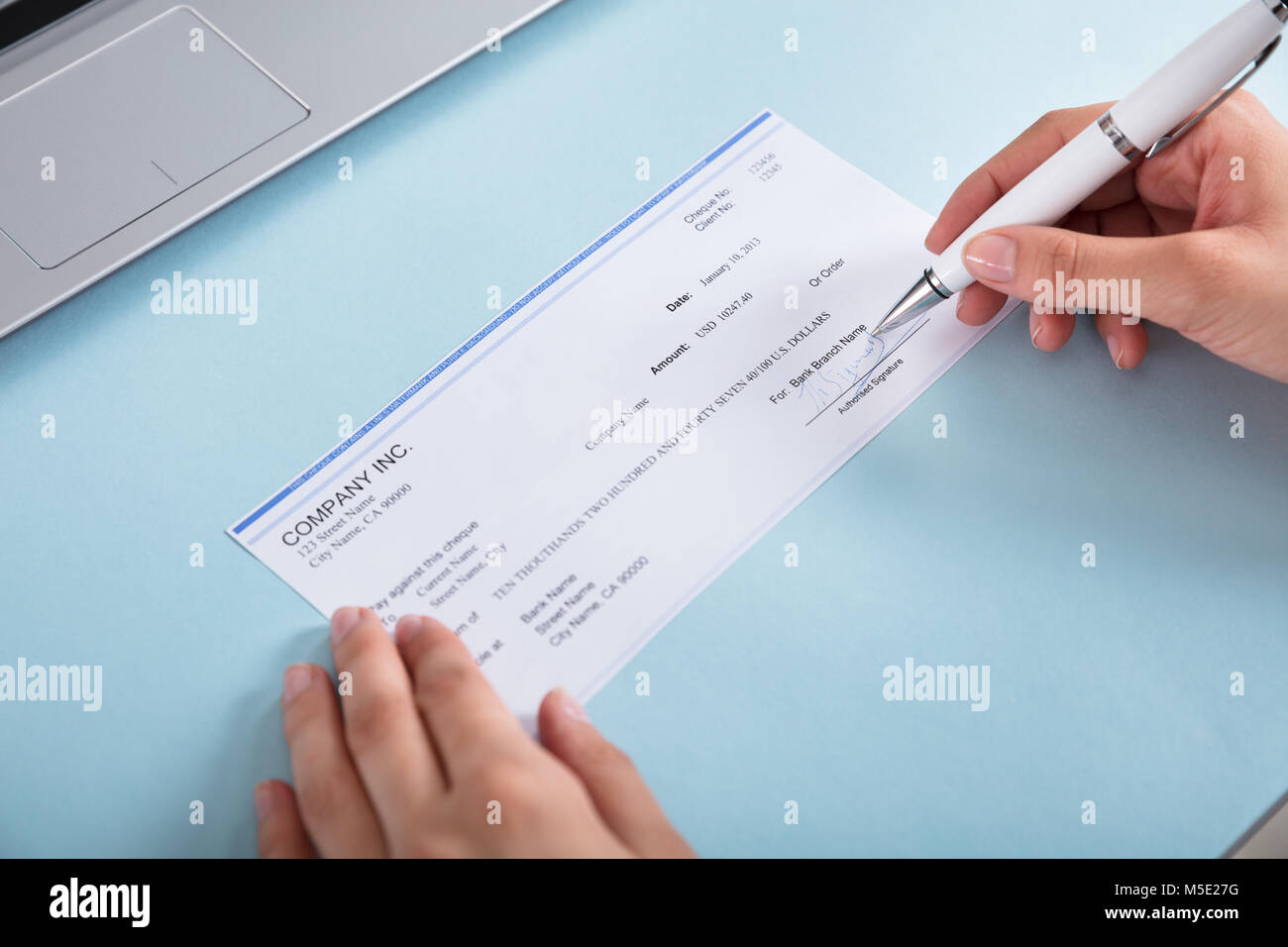 Businesswoman Signing The Company Cheque On Blue Desk Stock Photo - Alamy