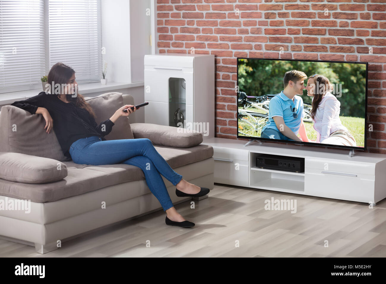 Young Woman Sitting On Couch Watching Television At Home Stock Photo ...