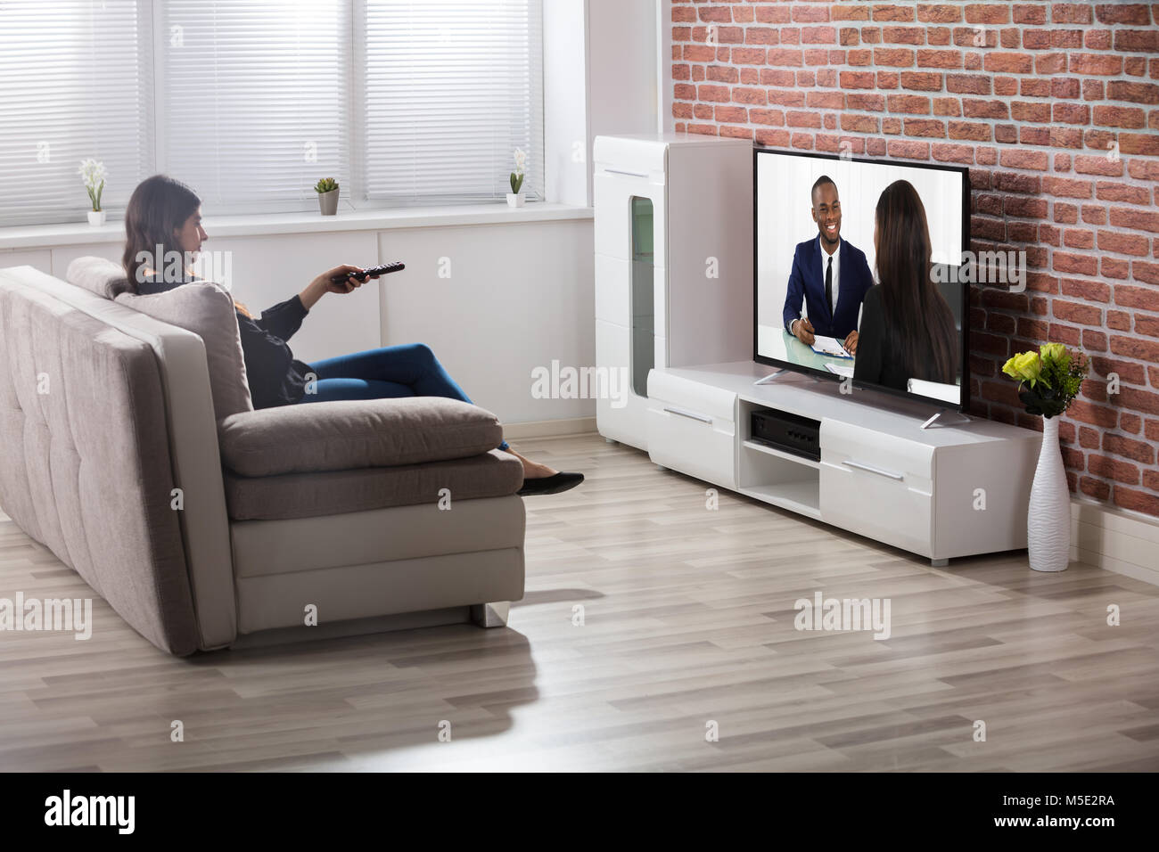 Young Woman Sitting On Couch Watching Television At Home Stock Photo ...