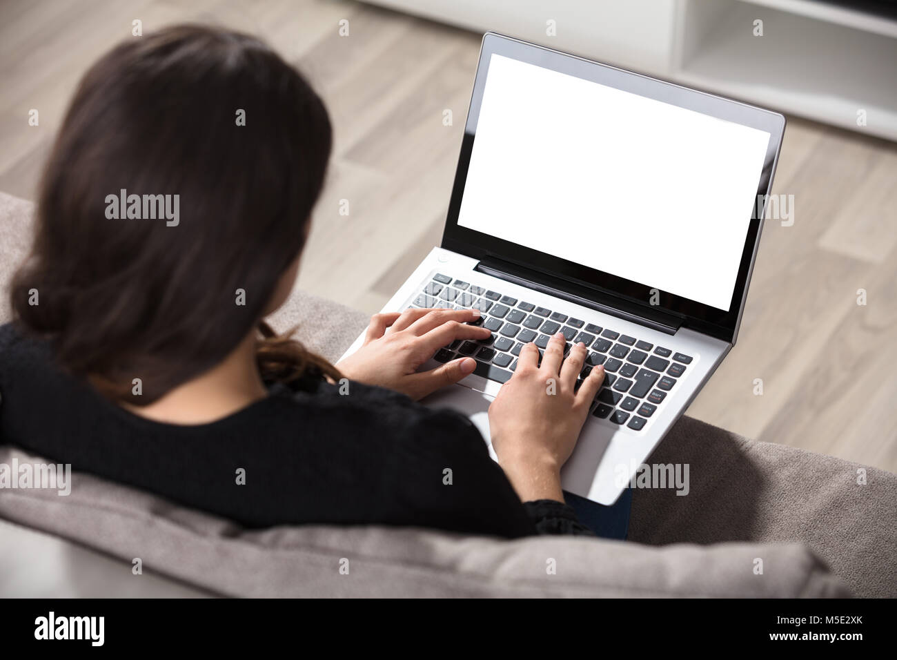 Rear View Of A Woman Sitting On Couch Using Laptop At Home Stock Photo ...