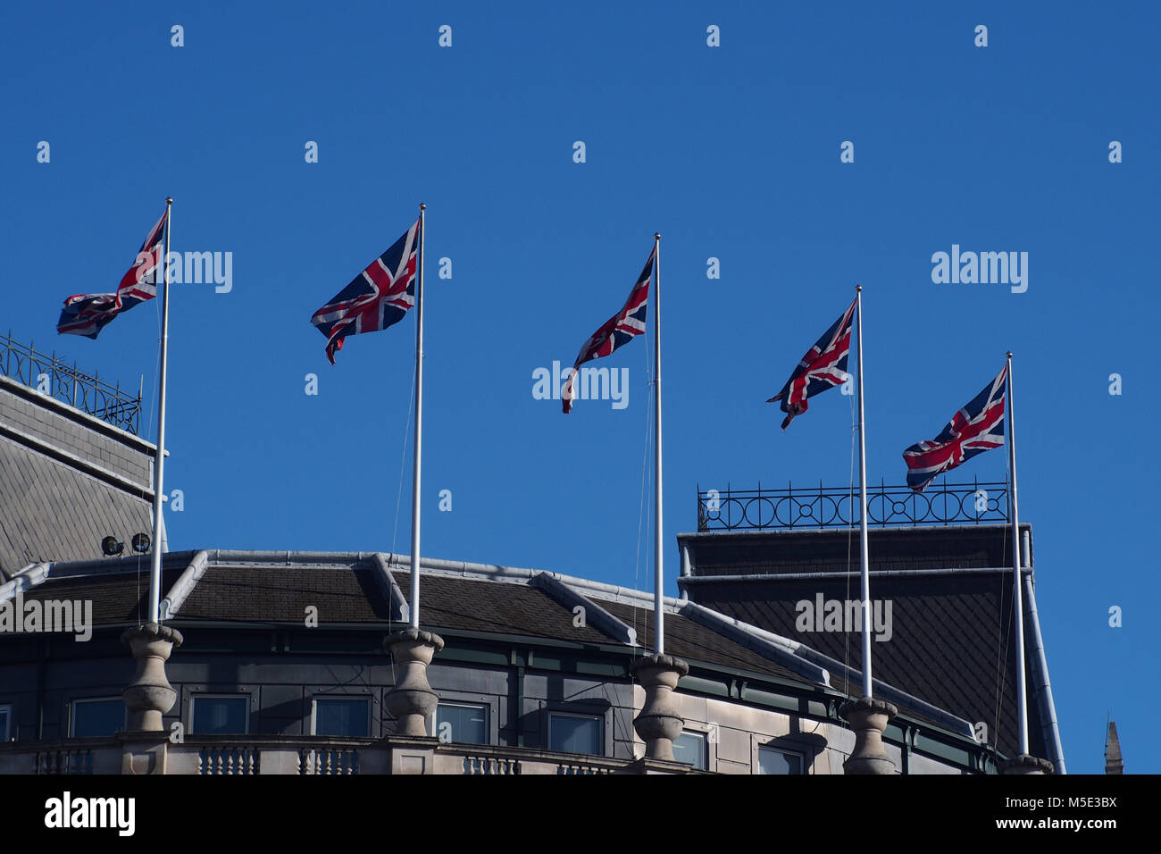 A row of Union flags flying on top of a building next to Trafalgar ...