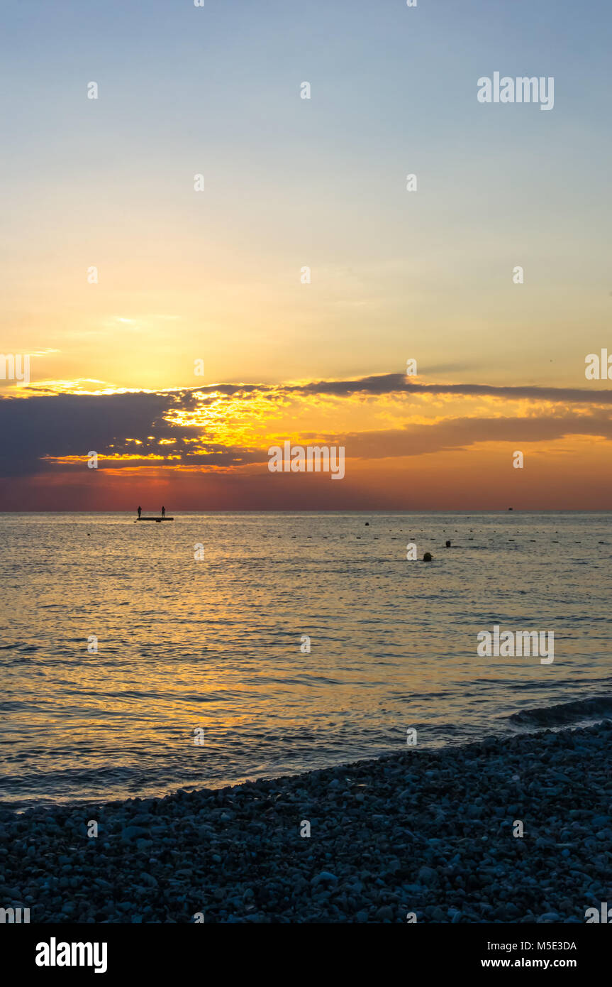 Summer sea sunset on the pebble beach, the sun, waves and clouds ...