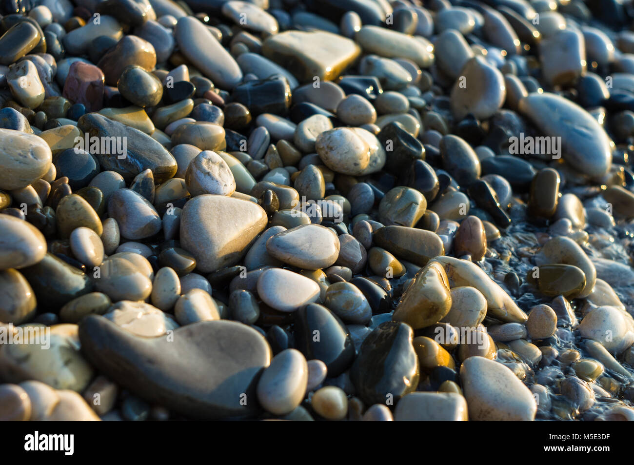 pebble stones on the sea beach on a warm summer day, the rolling waves ...