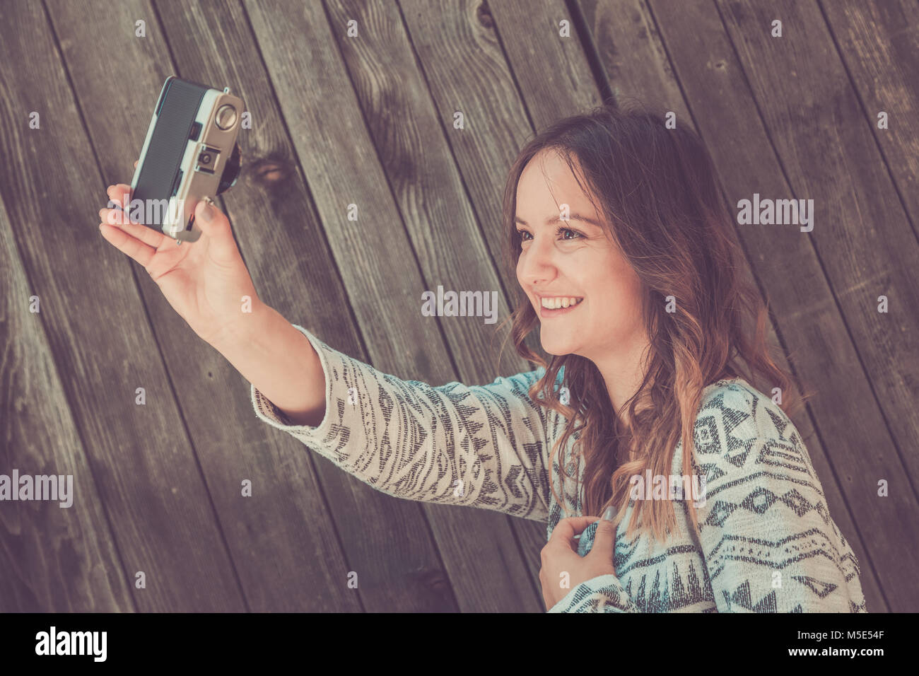 Portrait of young beautiful female taking self portrait by using retro ...