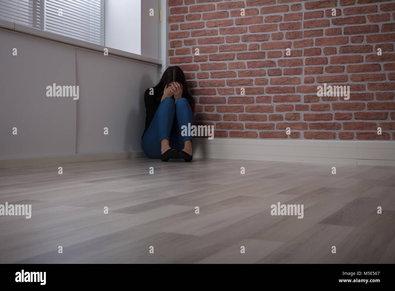 Young Woman Sitting On The Corner Of A Room With Fear At Home Stock ...