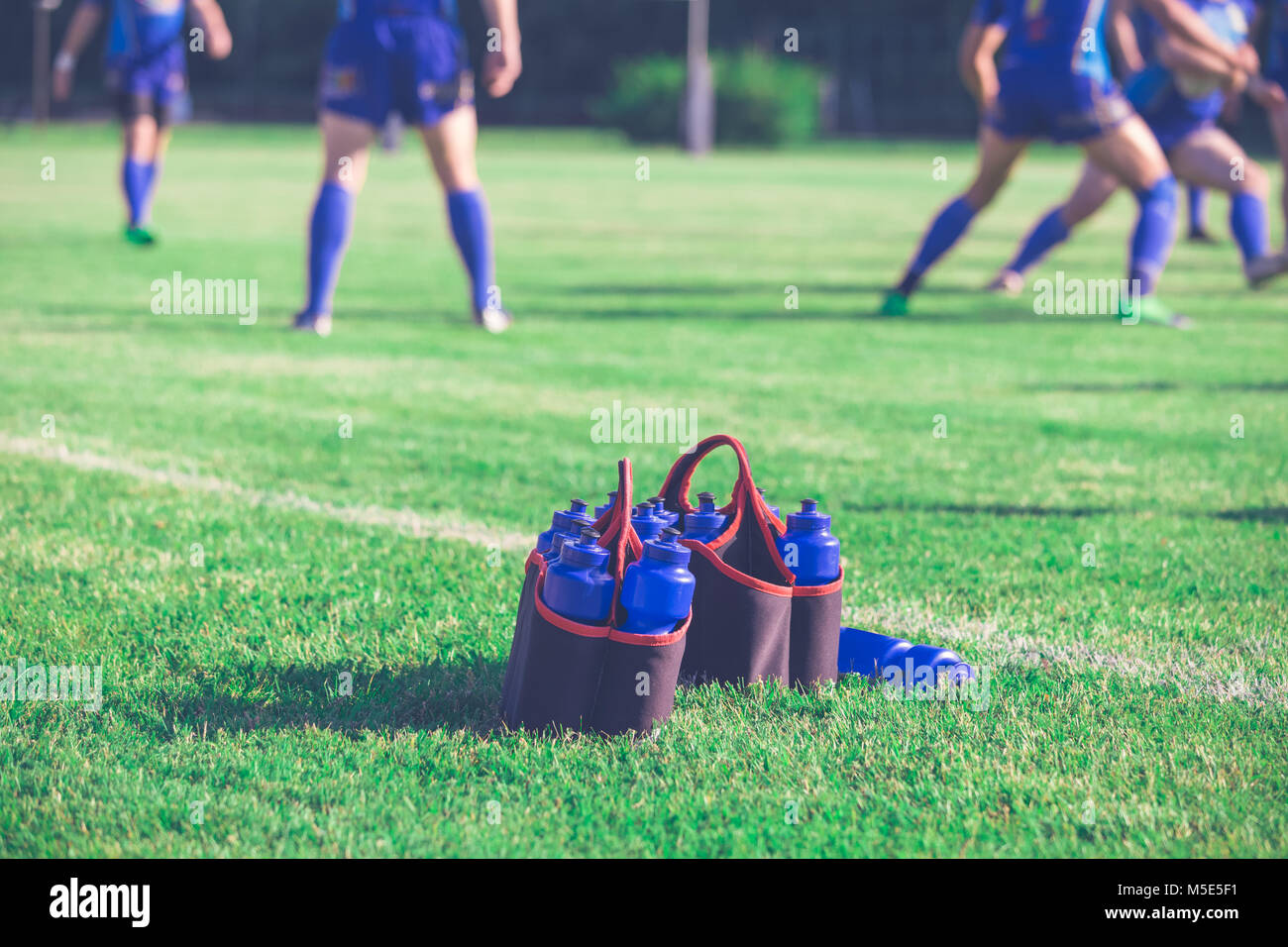 Sport bottles of fresh water energy drink on football rugby field grass ...